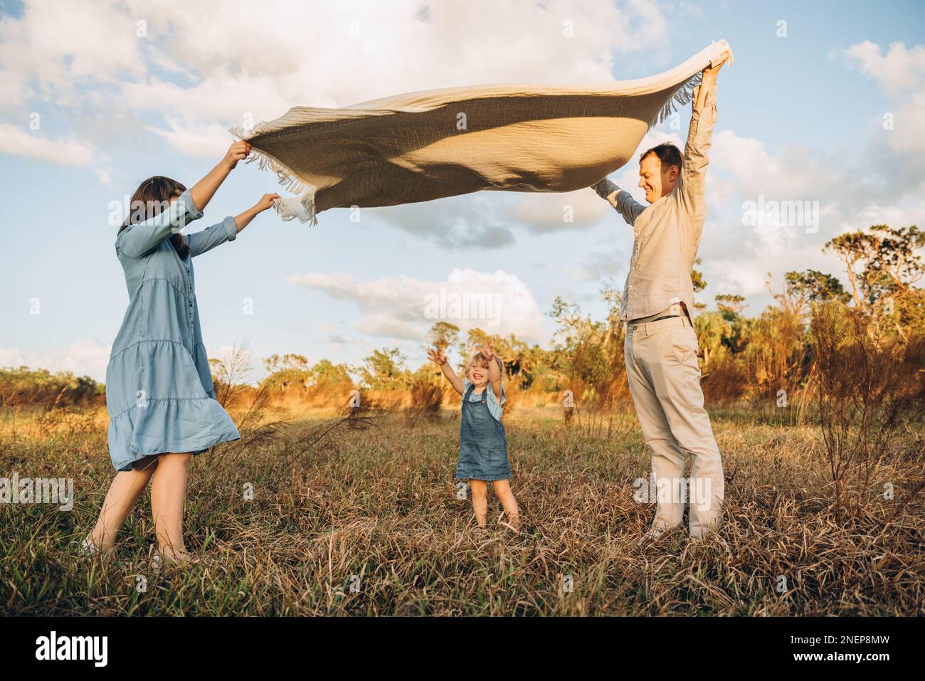 Young couple with cute 2 years old daughter under waving blanket Stock ...