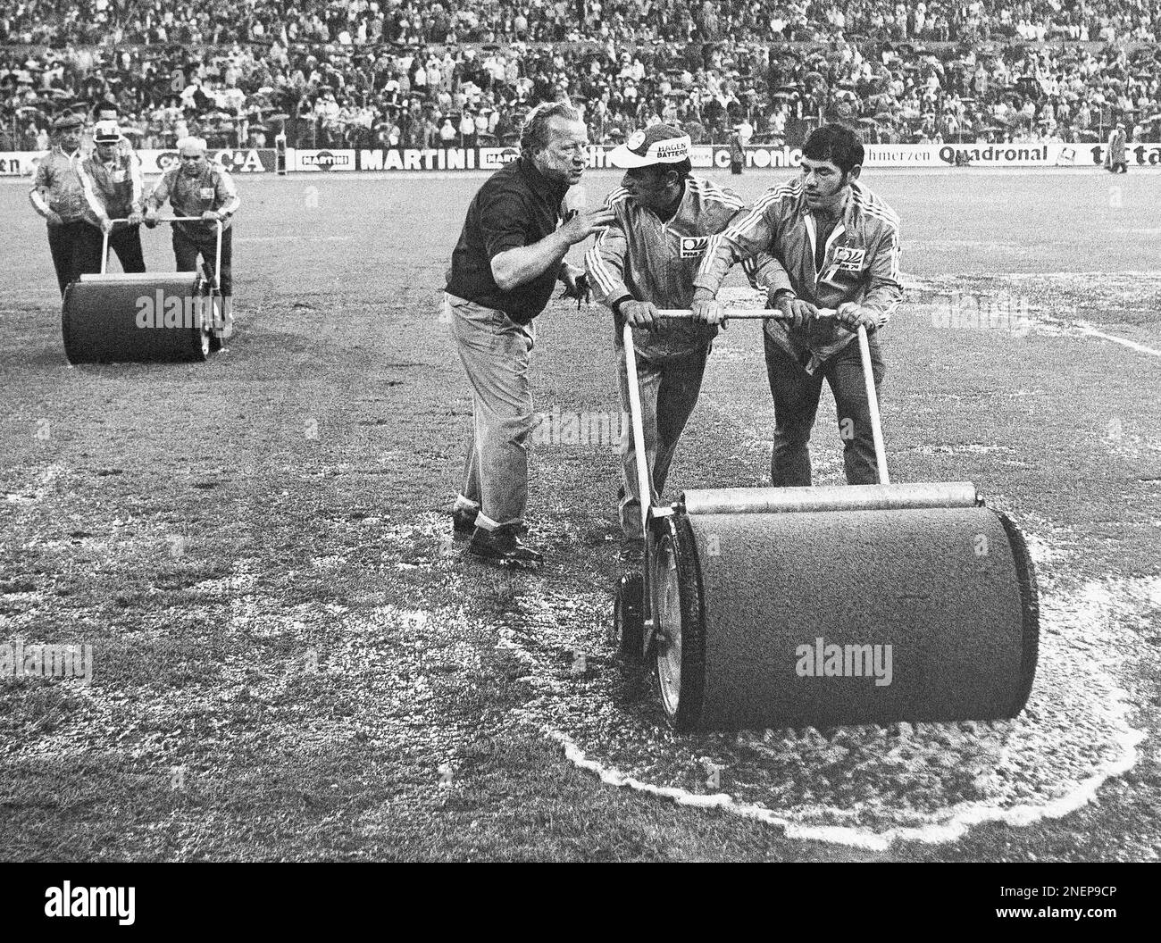 Ground staff push absorbent rollers across the flooded pitch following ...