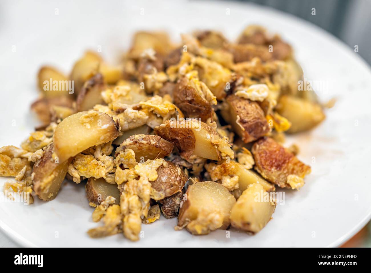 Macro closeup of breakfast or brunch cubed potatoes fried hash on white ...