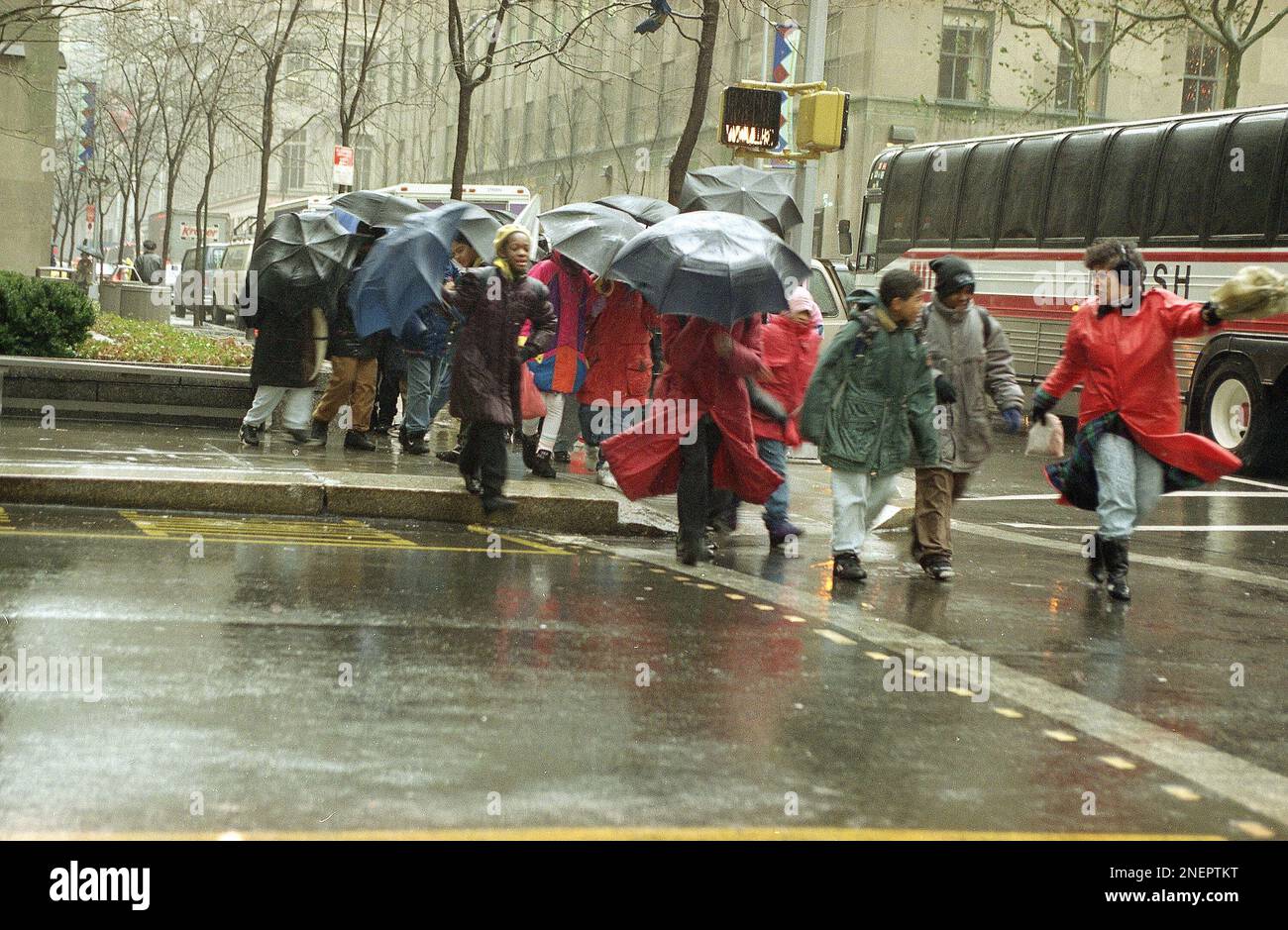 A school teacher, right, leads her class across rain swept Rockefeller ...