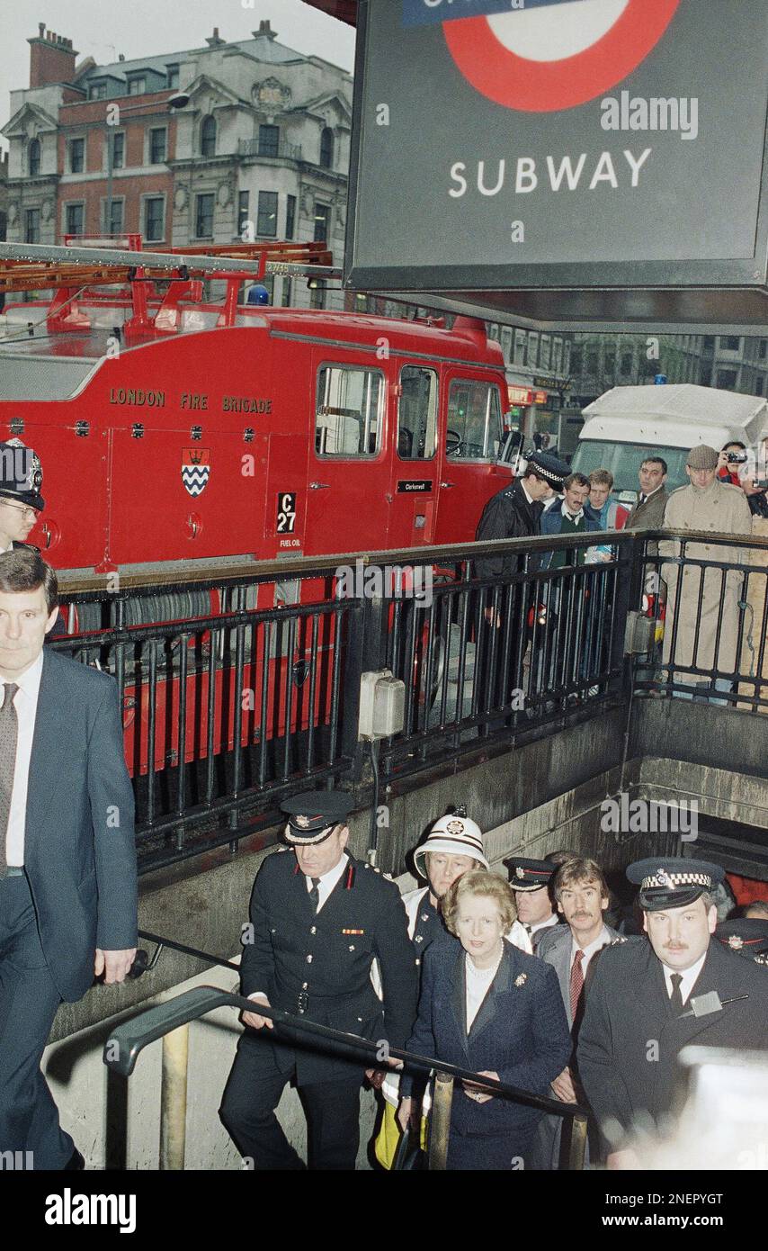 Fire officials escort the British Prime Minister Margaret Thatcher as ...