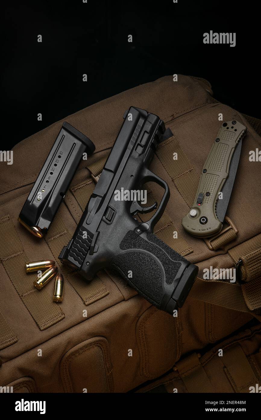 A pistol, cartridges for it and a folding knife on a brown backpack ...