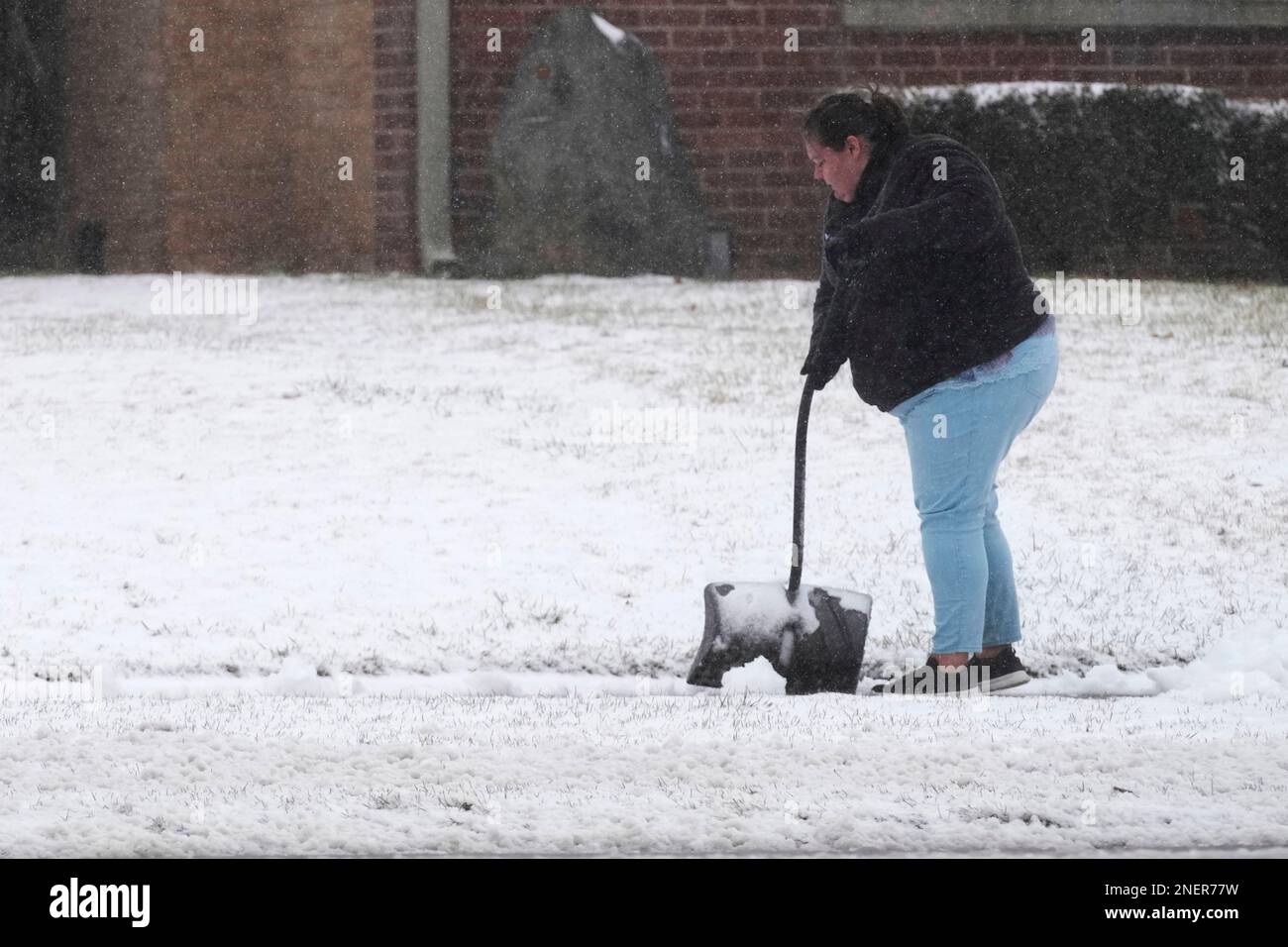 Woman clears snow from a sidewalk as a winter storm arrives Thursday, Feb. 16, 2023, in Wheeling ...