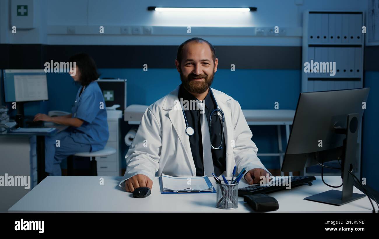 Portrait of practitioner doctor standing at desk checking disease ...