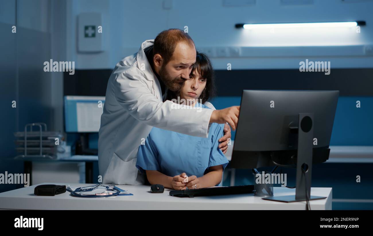 Nurse standing at desk typing medical expertise on computer while ...