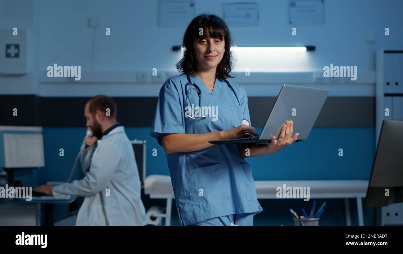 Assistant in blue uniform holding laptop computer analyzing patient ...