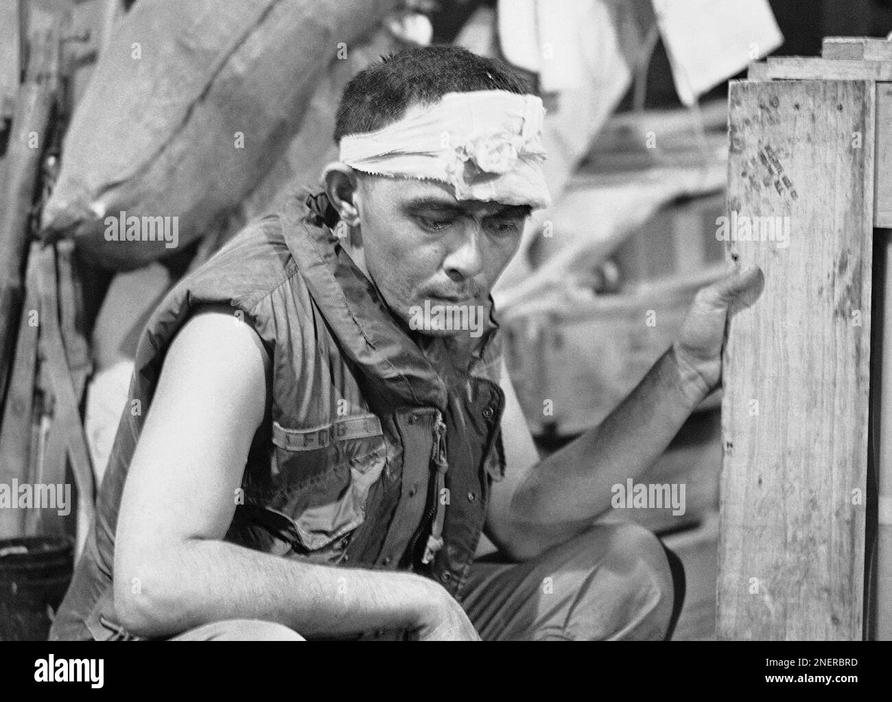 A wounded soldier, head bandaged, gives a hand to troopers and medics ...