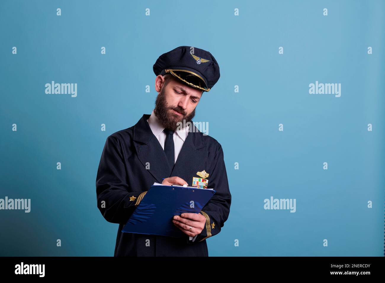 Airplane captain holding clipboard, concentrated pilot writing papers ...