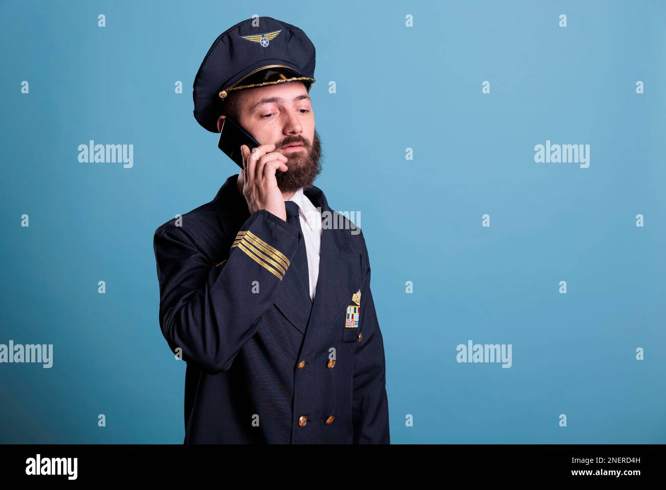 Middle aged pilot talking on smartphone, holding mobile phone, having ...