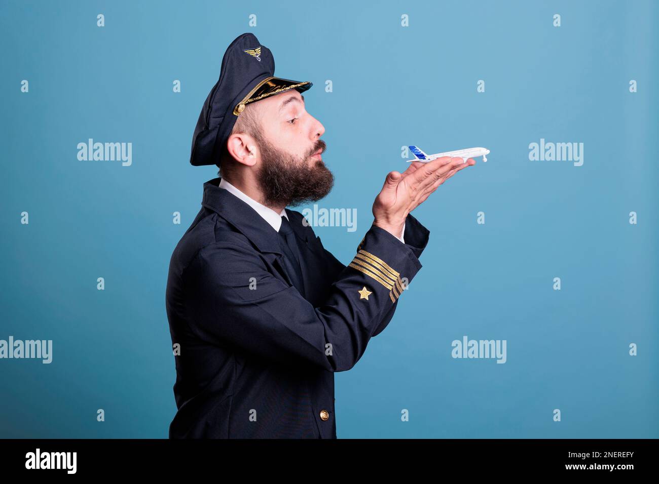 Airplane captain in uniform holding plane model in hands side view ...