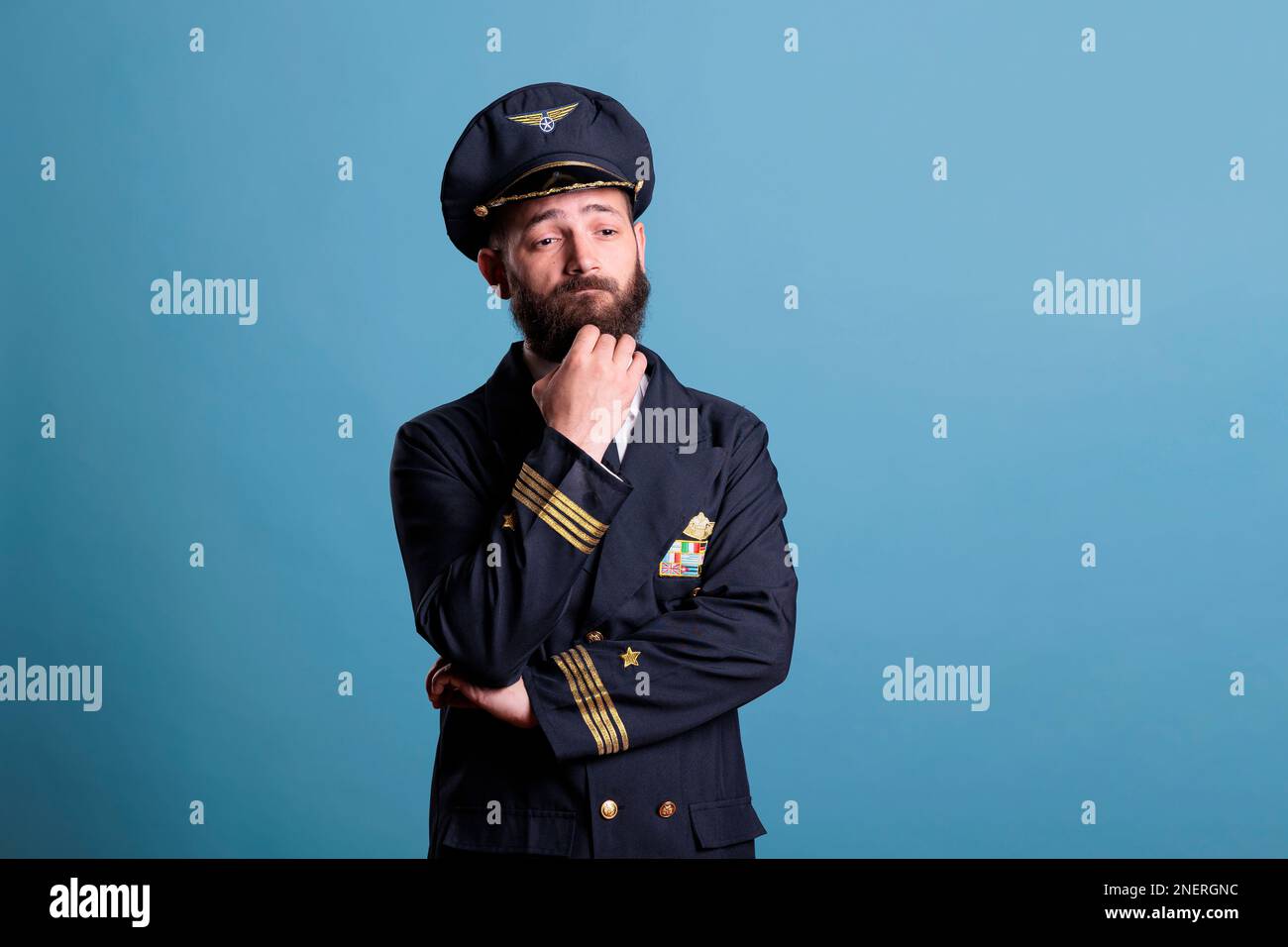 Pensive unsure airline pilot in uniform thinking, touching chin, making ...