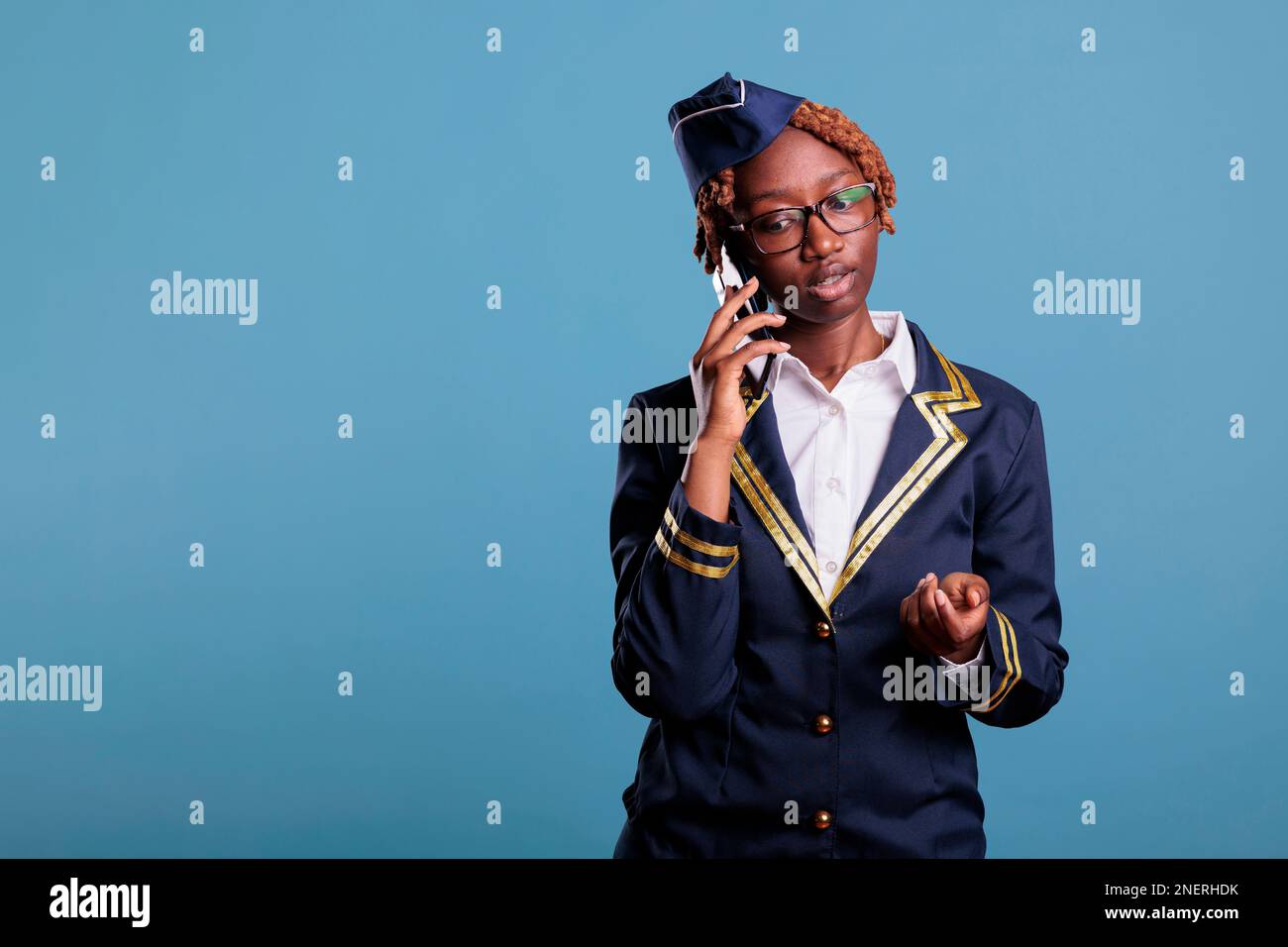 Concentrated female flight attendant talking on the phone dressed in ...