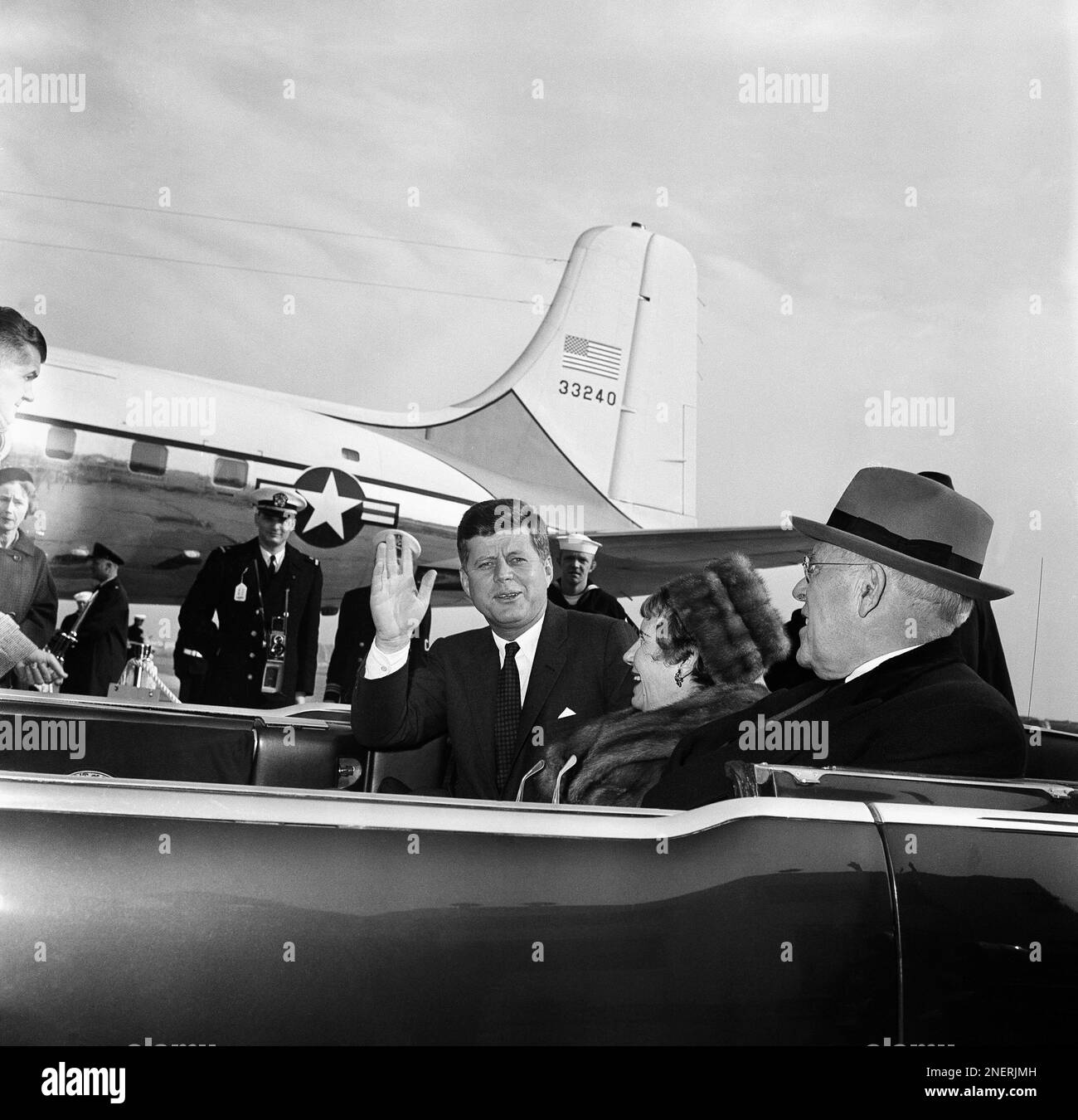 President John Kennedy waves a greeting from car after he landed at ...