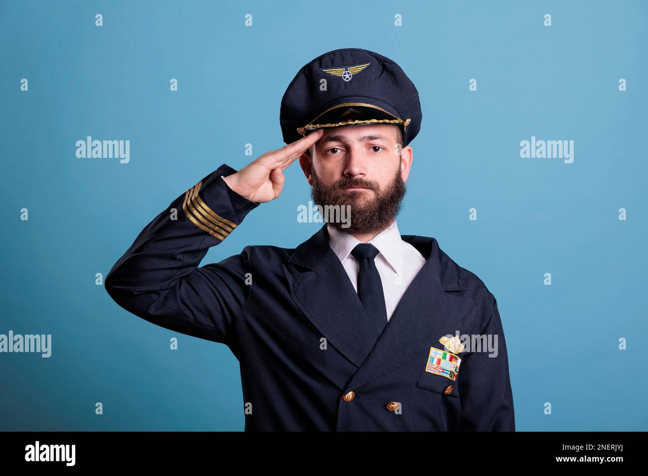 Serious aviation academy airplane pilot saluting, wearing uniform and ...