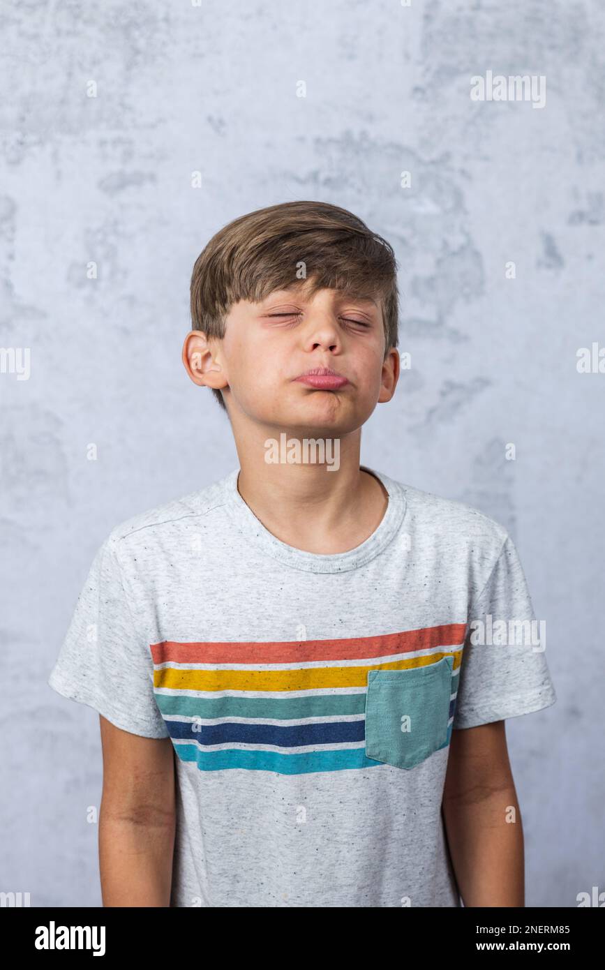 A cute little boy with autism in a studio setting making a pouty face ...