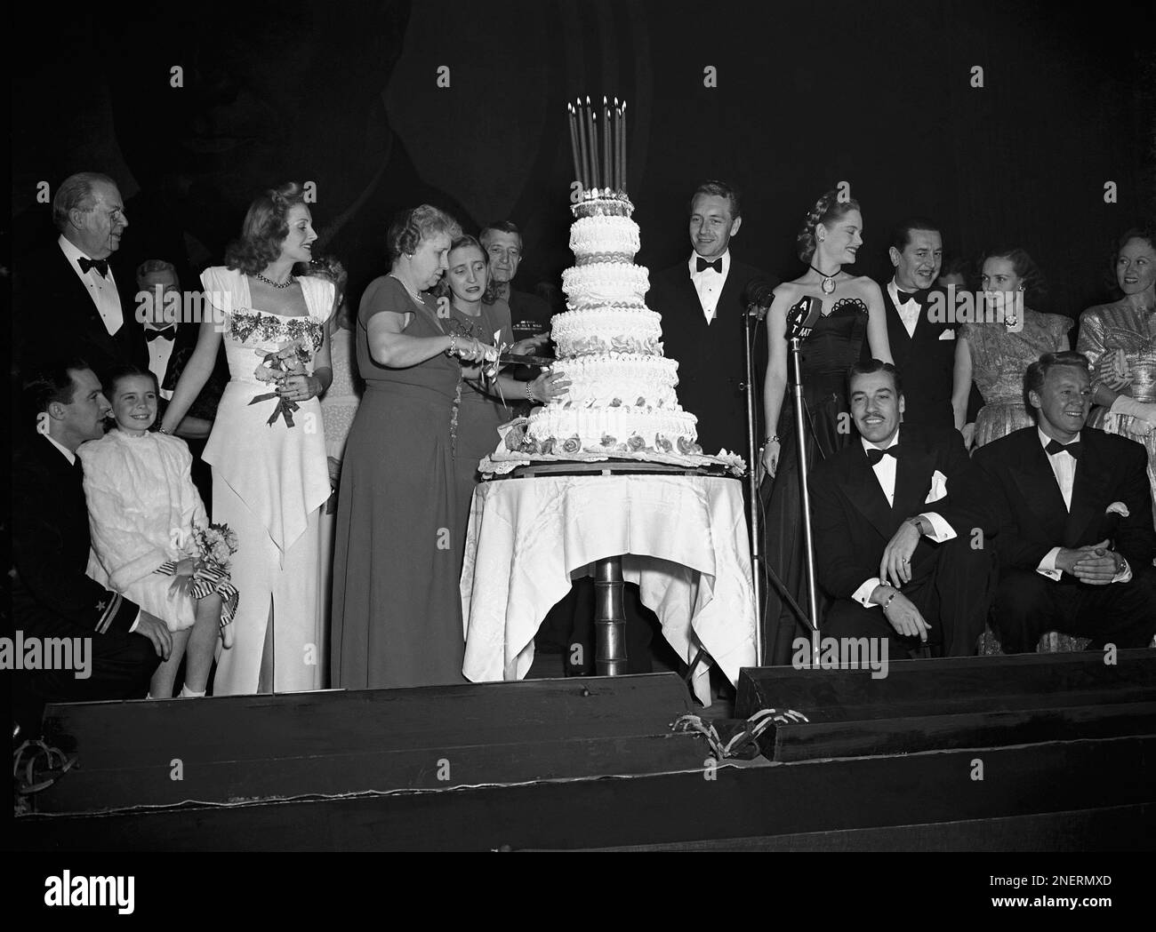 Knife poised, Mrs. Bess Truman, wife of the President, begins cutting ...