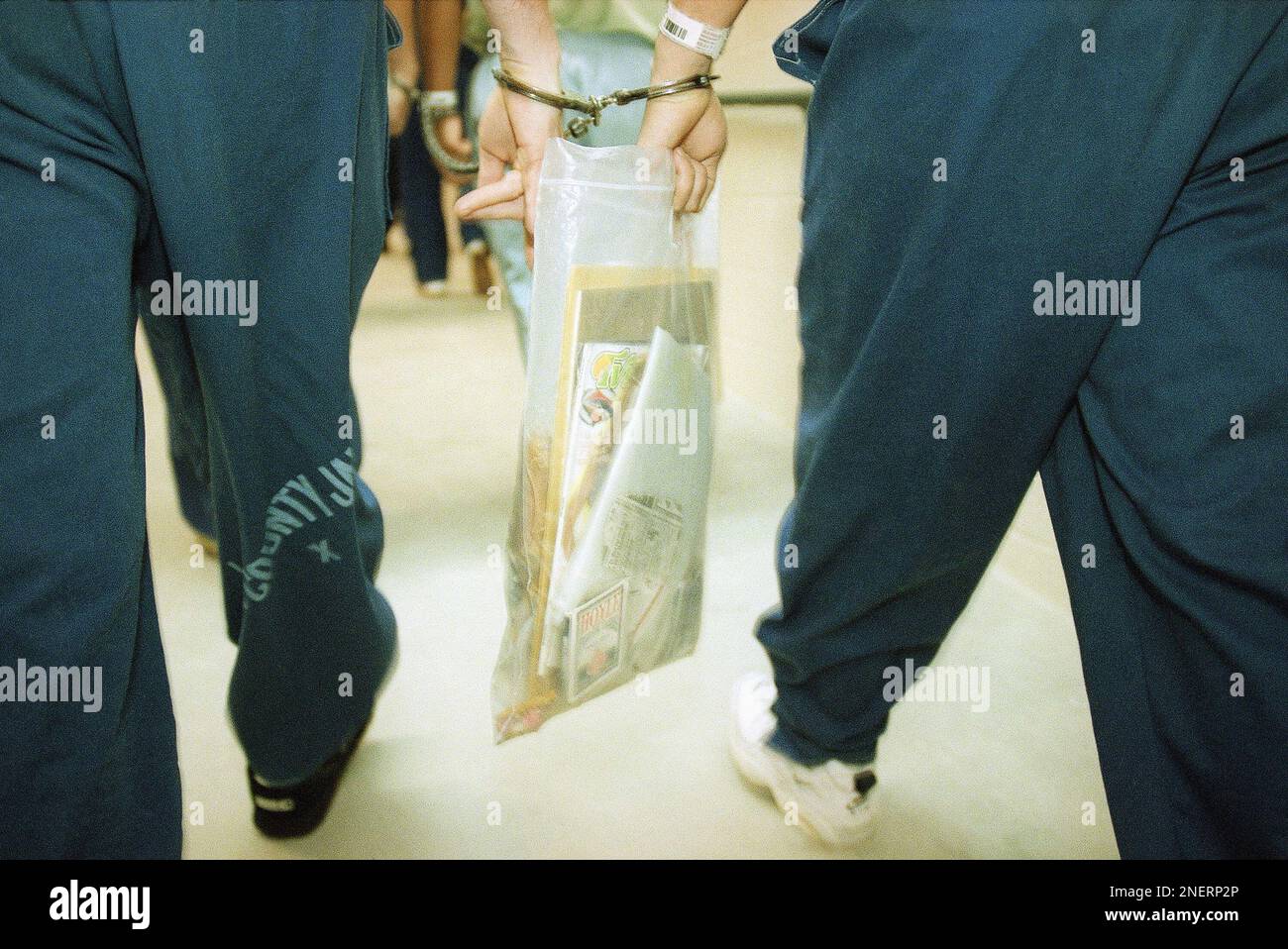 Handcuffed inmates carry personal belongings as they are transferred to ...