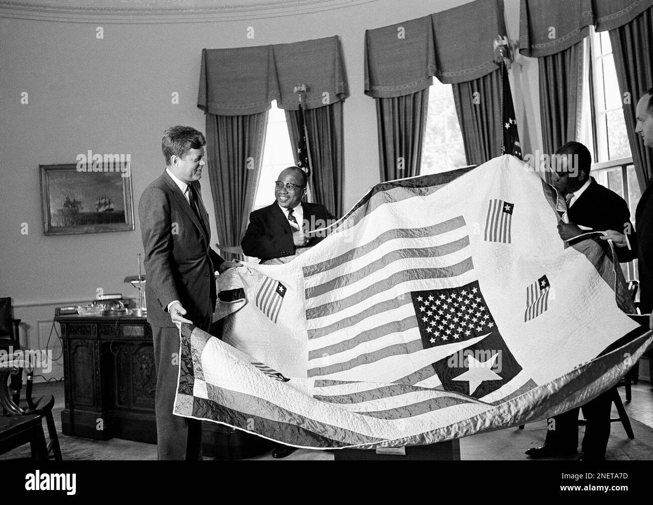 President John Kennedy helps hold a gift presented to him at the White ...