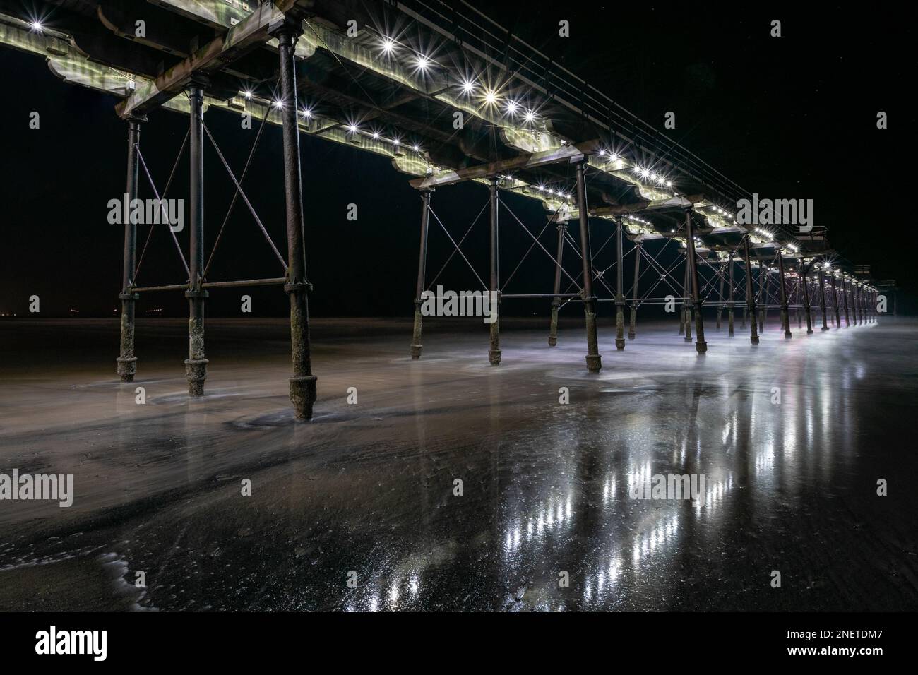 Lights reflected in the wet sand at night Stock Photo - Alamy