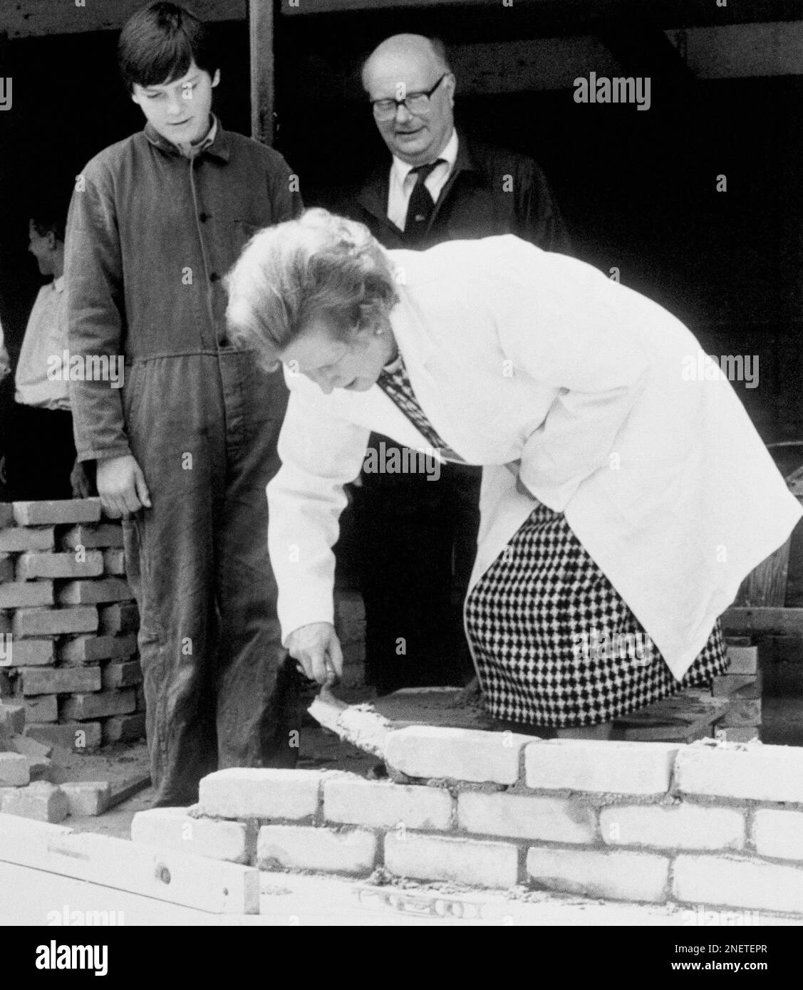 Prime Minister Mrs. Margaret Thatcher tries her hand at bricklaying ...