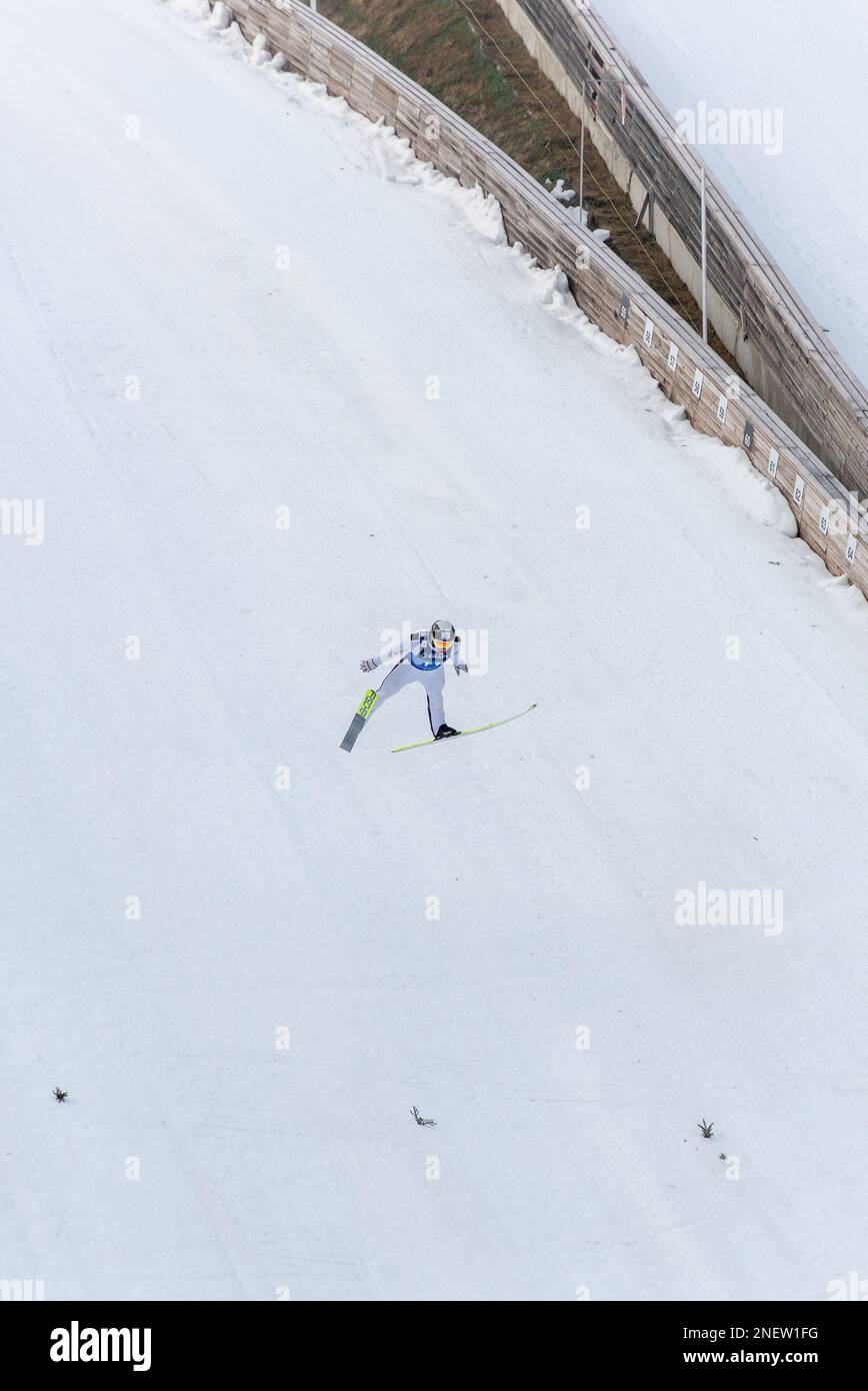 A Ski jumper sliding at high speeds down a snowy hill at a ski resort ...
