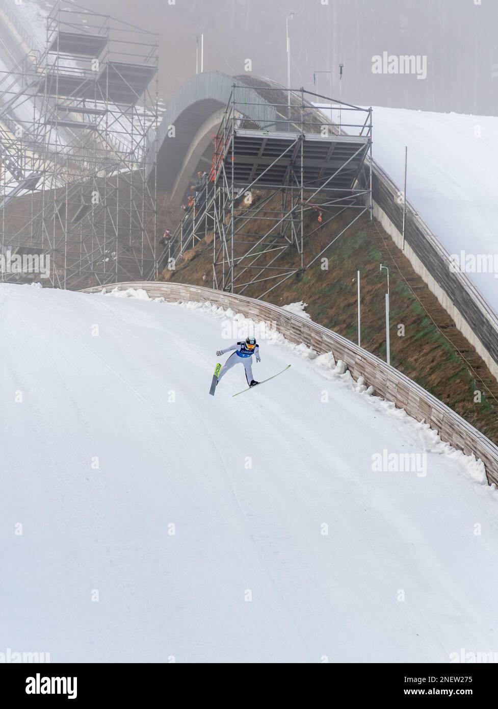 A ski jumper leaping high over a snow-covered ramp at a ski resort in ...
