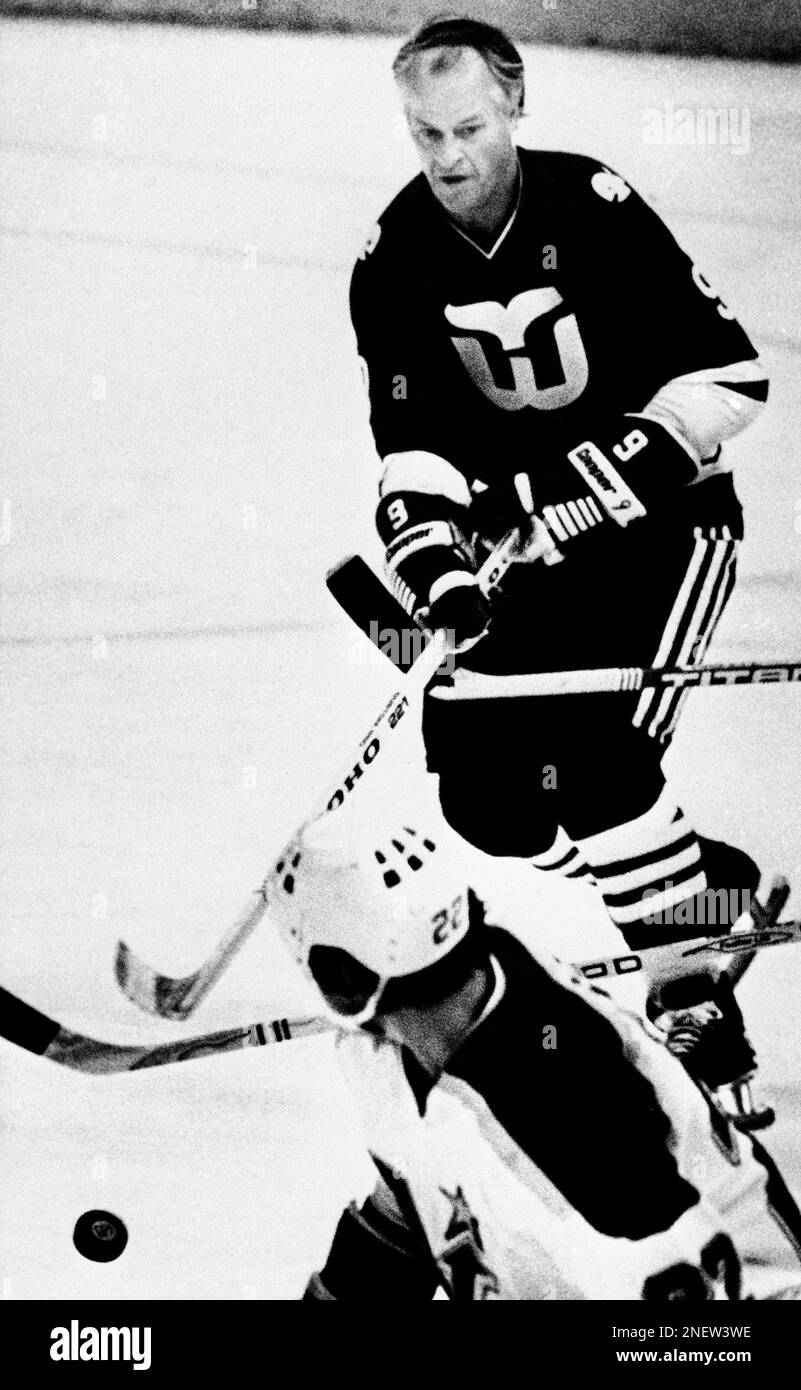 Gordie Howe (9) makes a pass under watchful eyes of North Stars Gary ...
