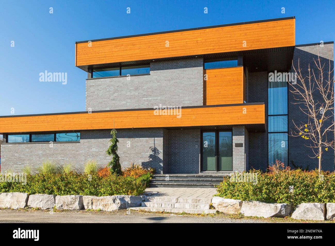 Modern grey brick and stained wood finish cube style house facade with ...