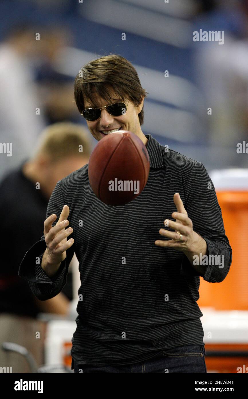 Actor Tom Cruise catches a football on the sidelines before the ...
