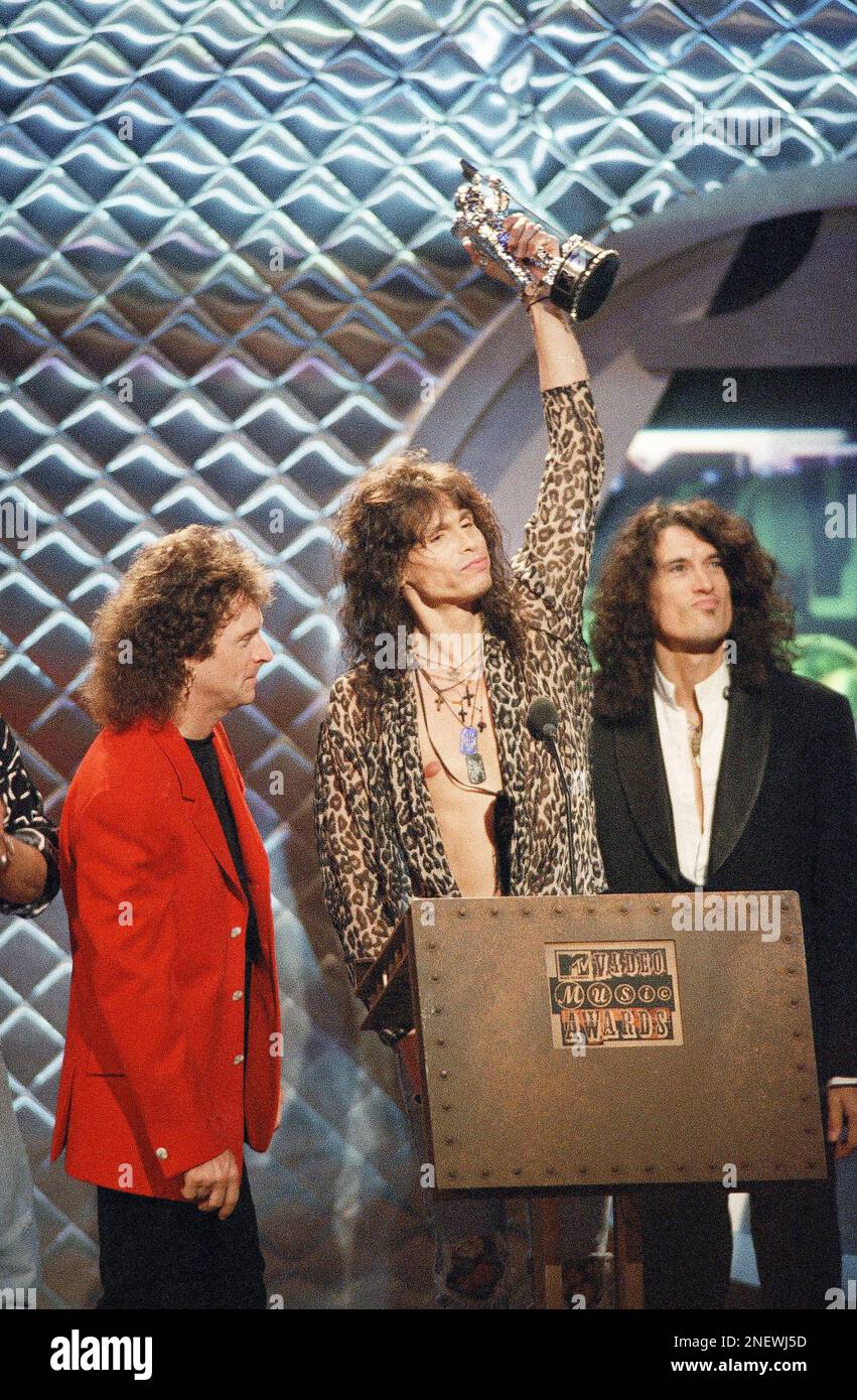 Steven Tyler, center, lead singer of Aerosmith holds up the trophy the ...