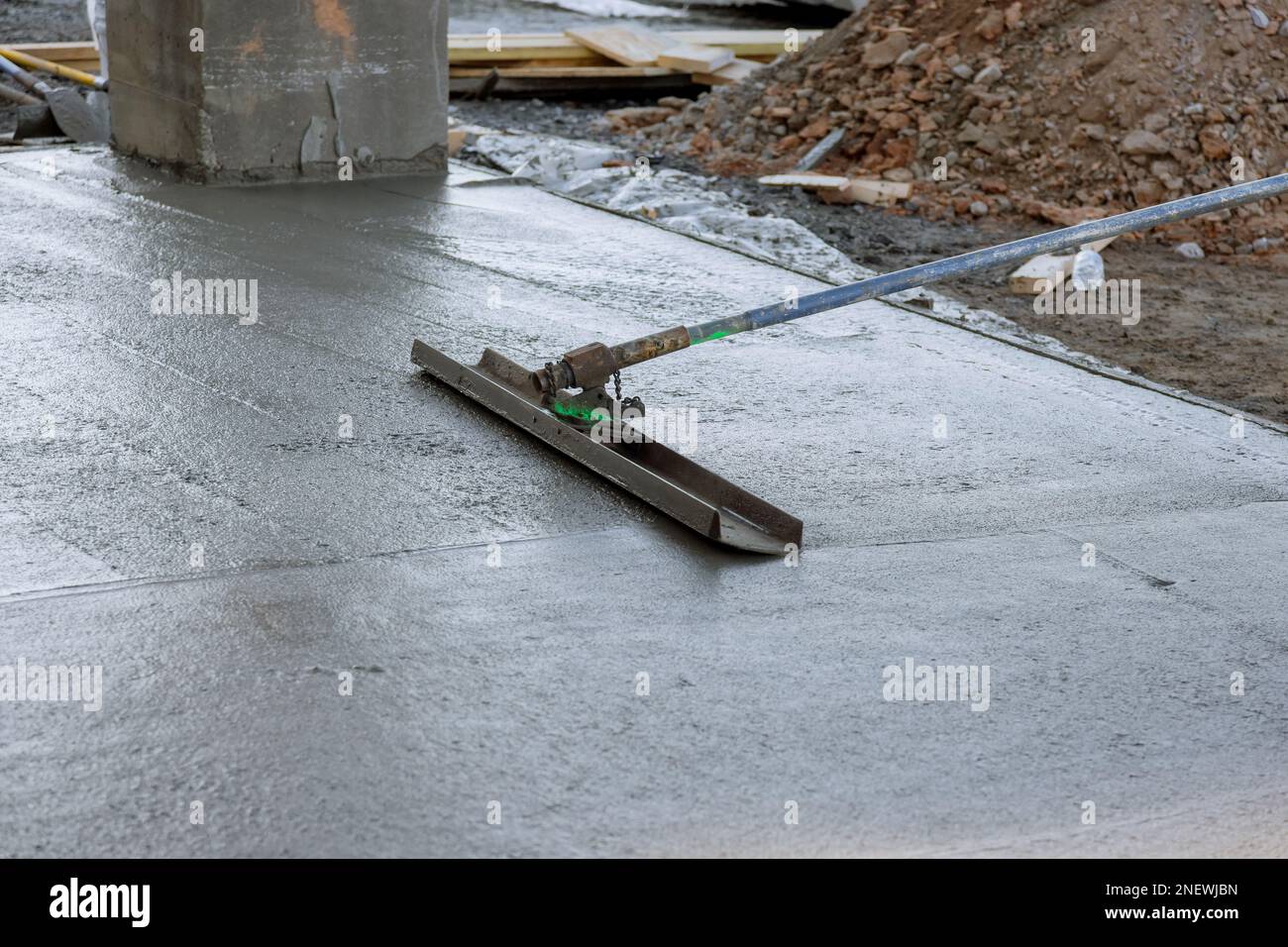 Using long trowels worker in construction site leveled wet cement ...