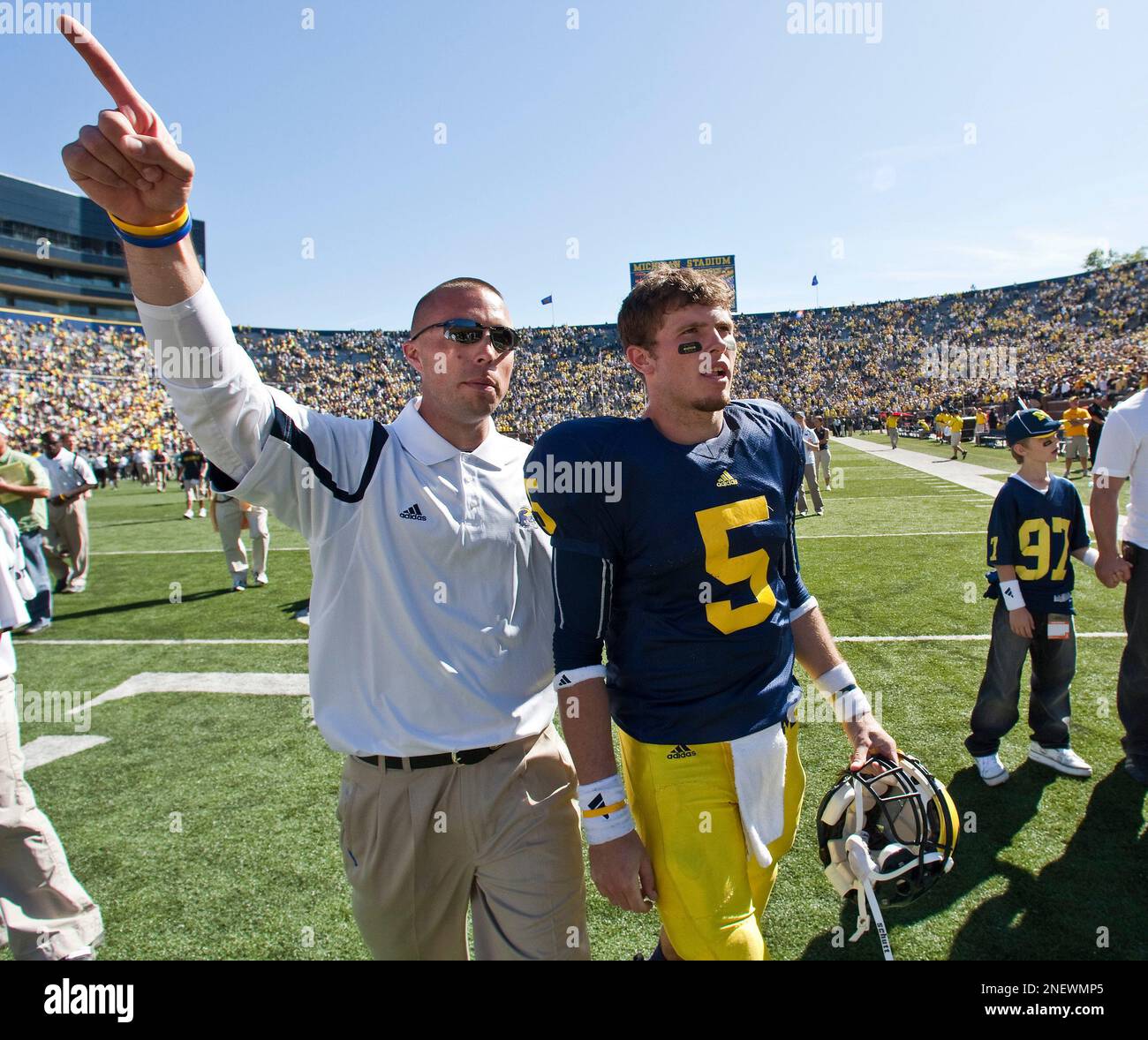 Michigan coaching staff member Josh Ison, left, accompanies quarterback ...