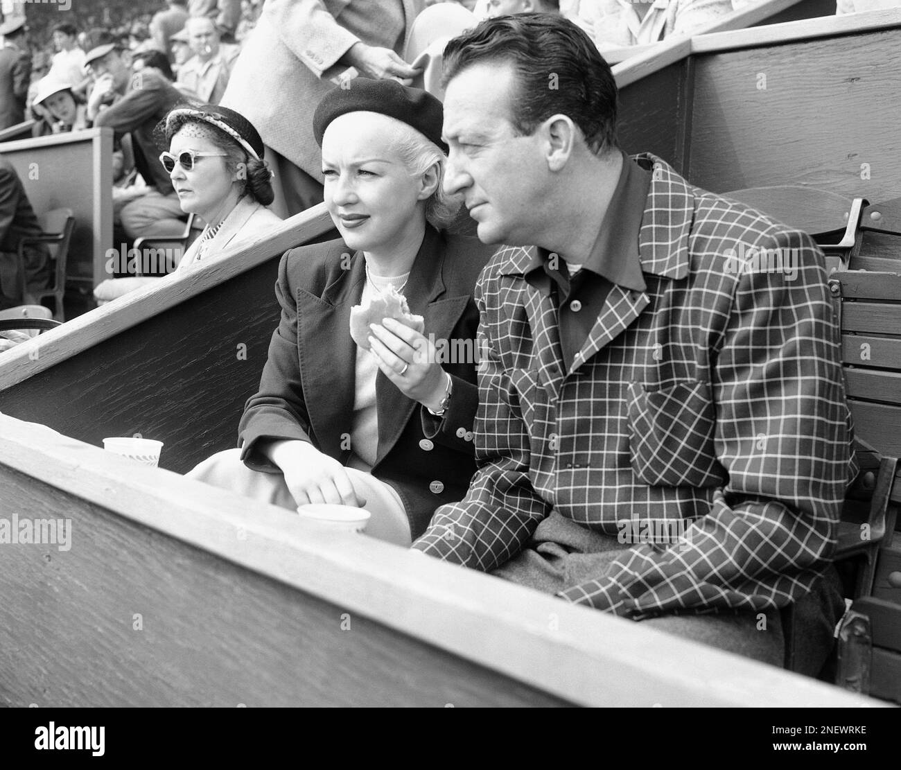 Screen favorite Betty Grable holds a half eaten sandwich as she watches ...