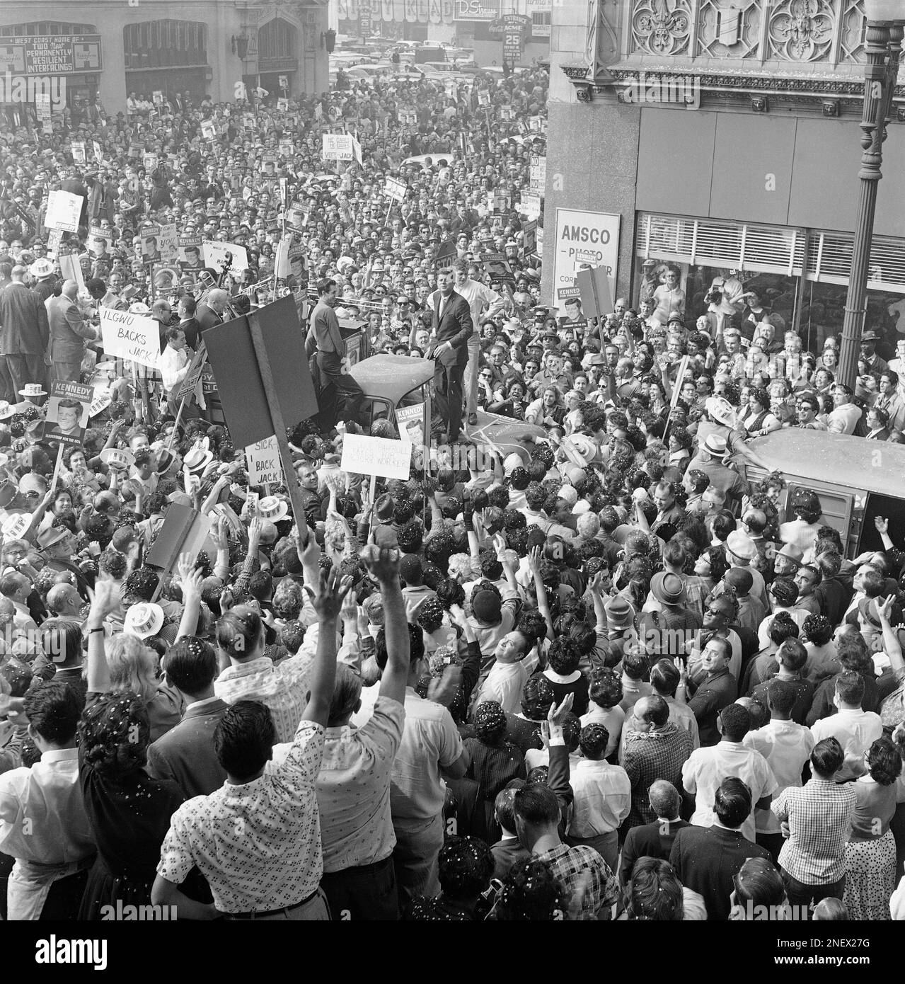 Sen. John F. Kennedy stands on the hood of a truck to acknowledge the ...