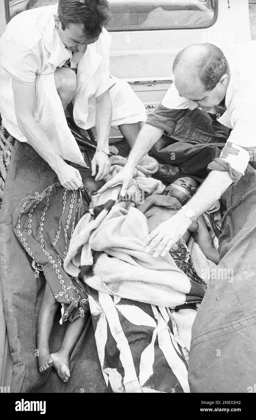 A European red cross attendant places a blanket over the bodies of a ...