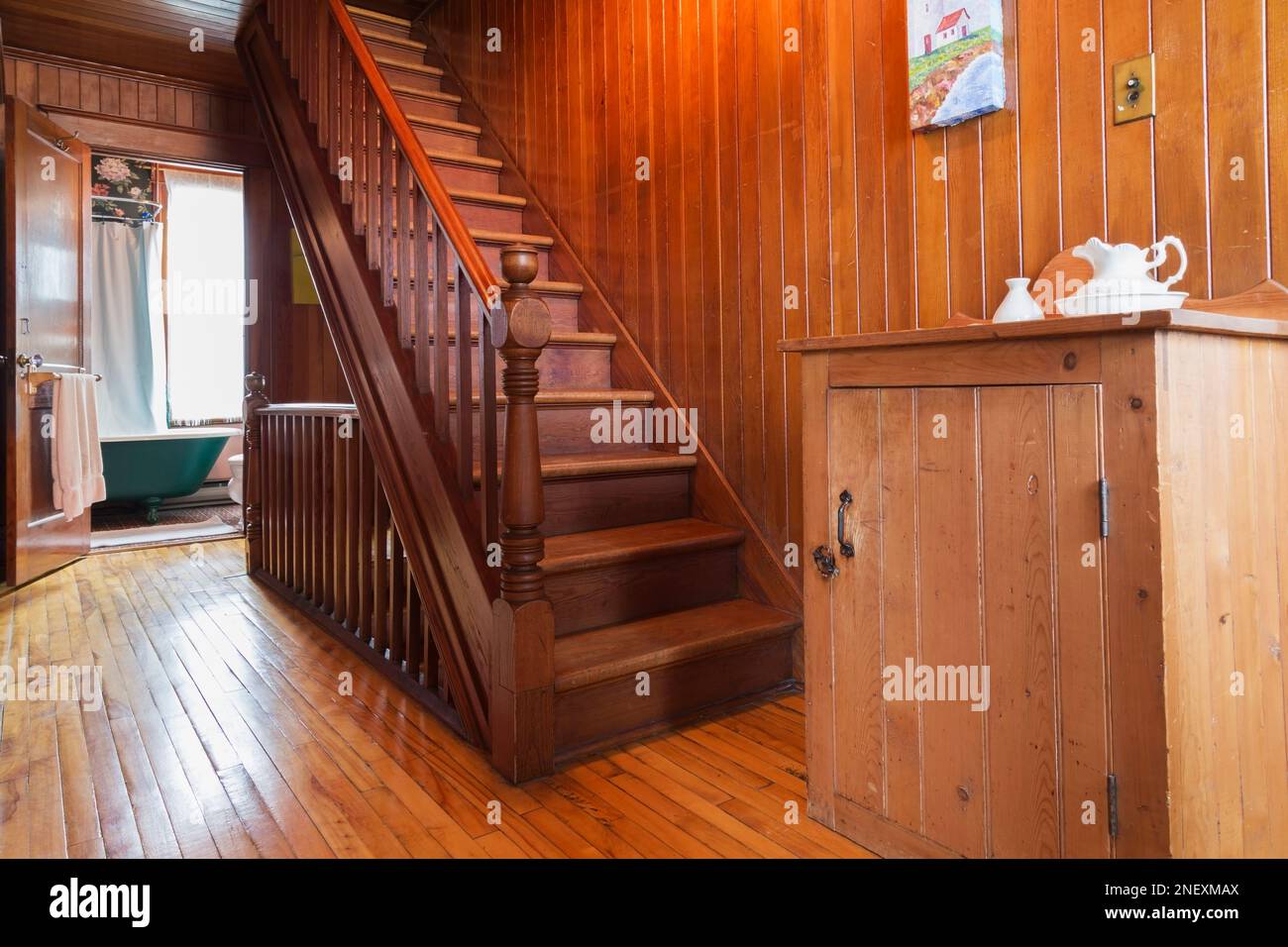 Washstand and wooden staircase leading to attic and opened door of main ...