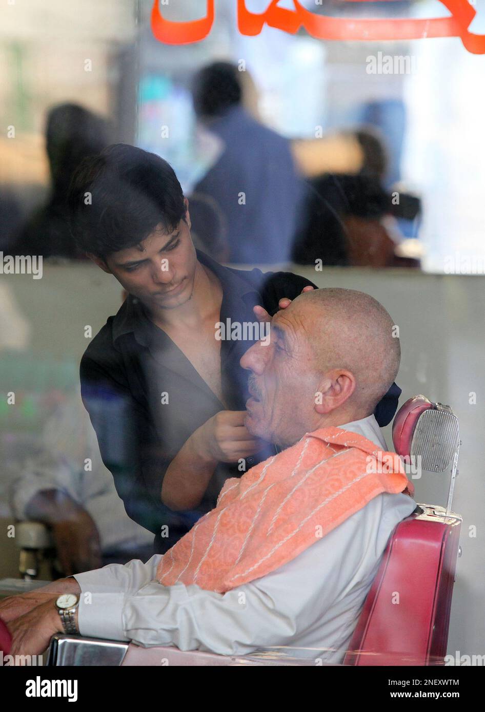 A young Jordanian barber is seen cutting the hair of an old man in the Jordanian coastal town of ...