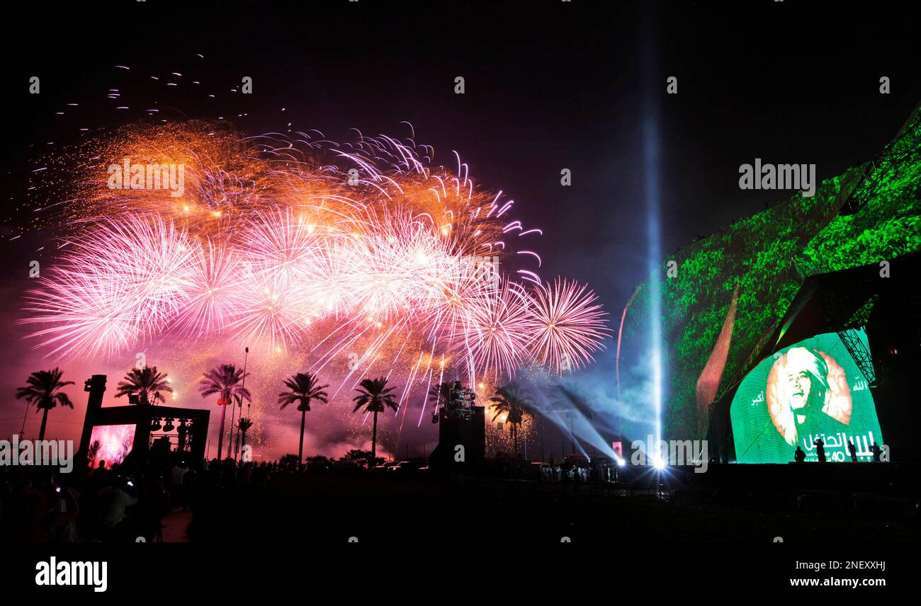 Fireworks launched from ships explode over palm trees next to a ...