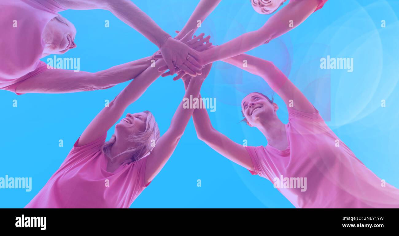 Composition of smiling friends stacking hands on blue background ...