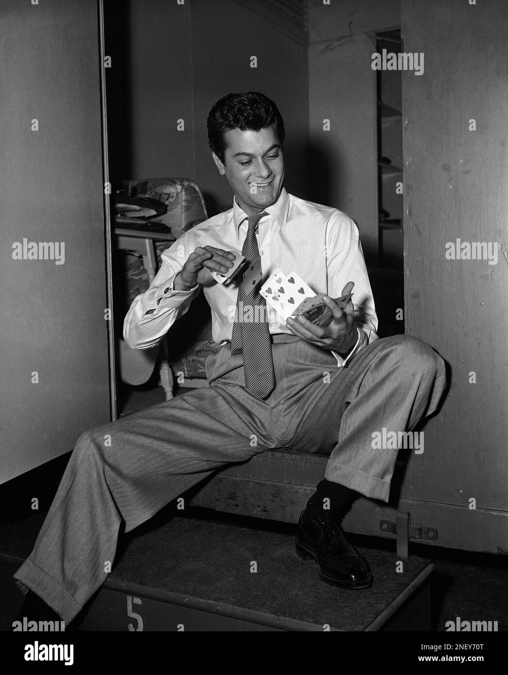 Film actor Tony Curtis executes a card trick for the photographer as he ...