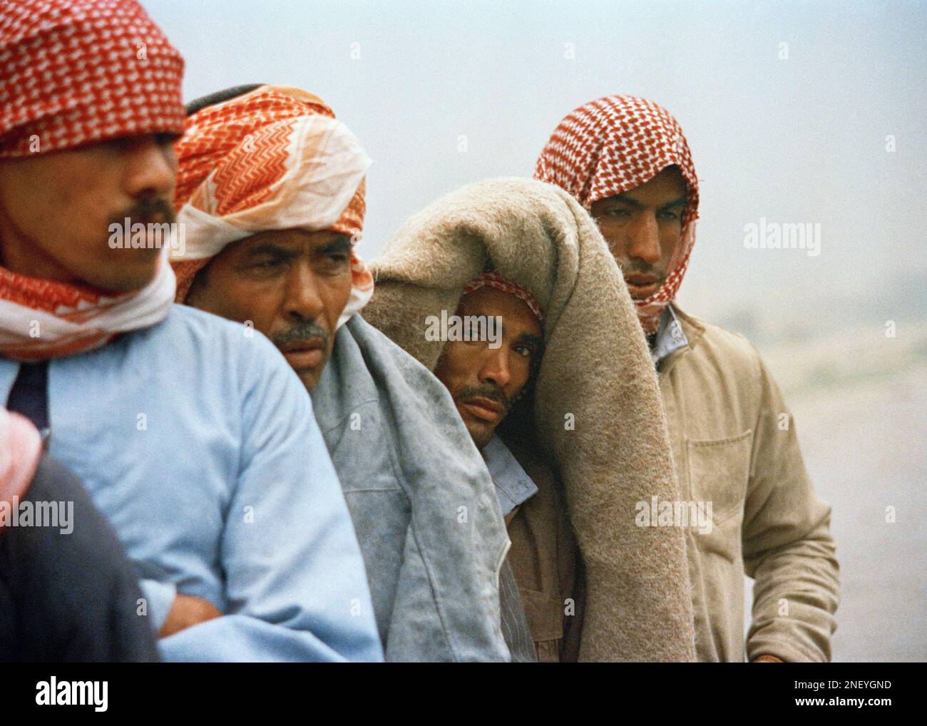 Kuwaiti refugee men cast glances toward a checkpoint just outside ...