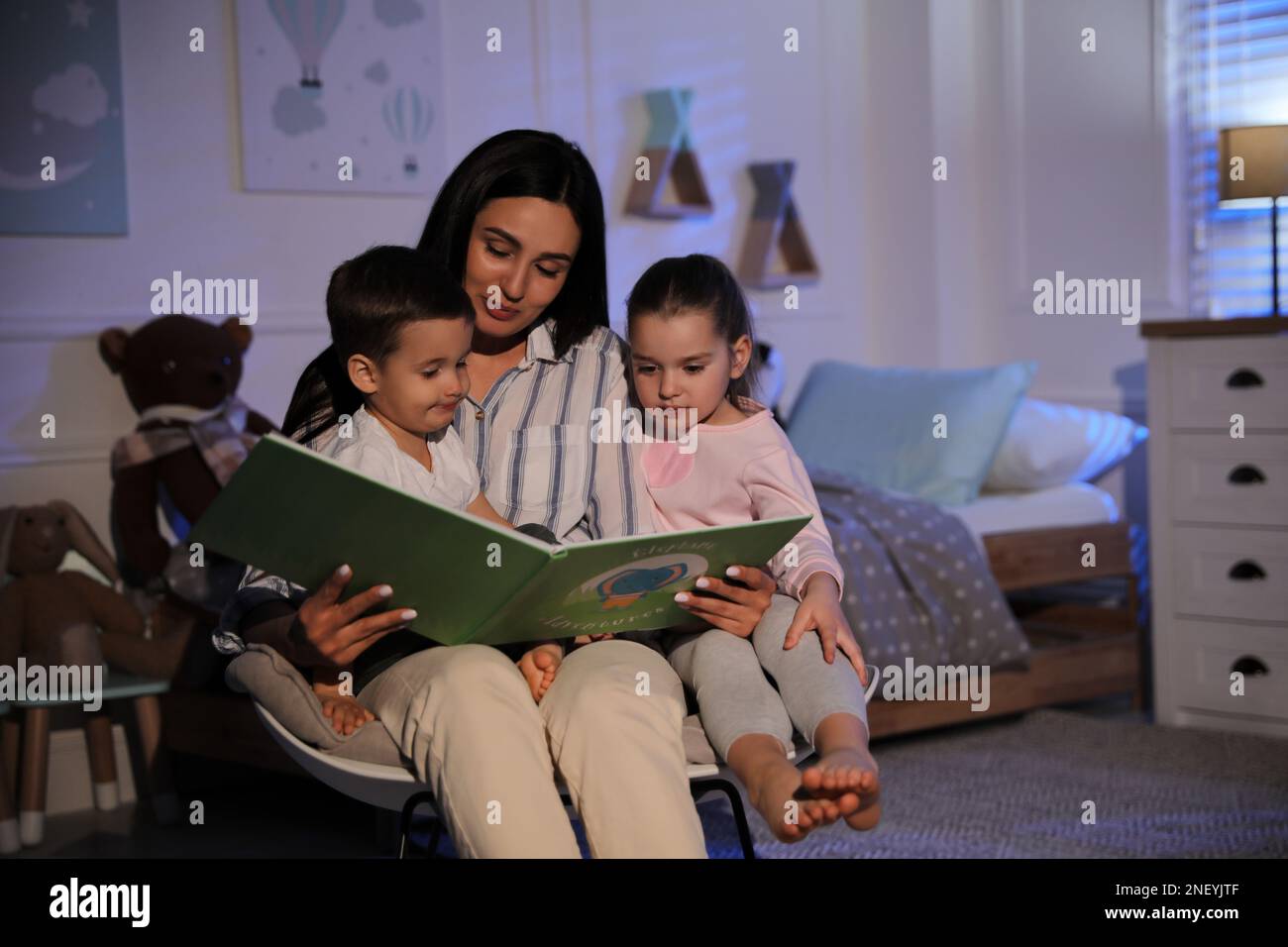 Mother reading bedtime story to her children at home Stock Photo - Alamy