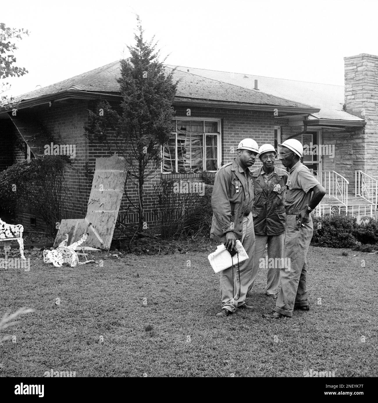 Three black Civil Defense workers stand guard in front of the home of ...