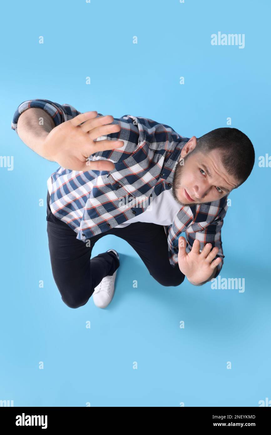 Man evading something on light blue background, above view Stock Photo ...