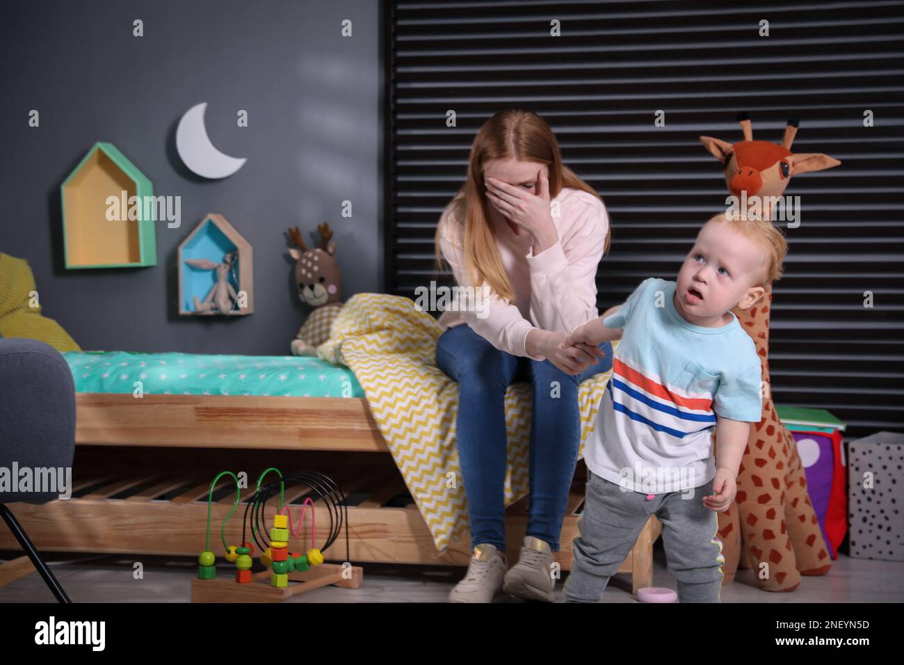 Depressed single mother with baby in children's room Stock Photo - Alamy