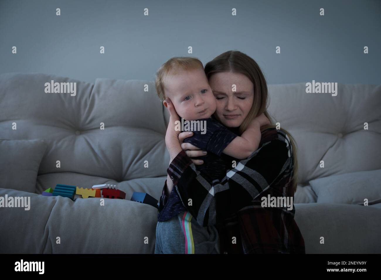 Depressed single mother hugging her child in living room Stock Photo ...