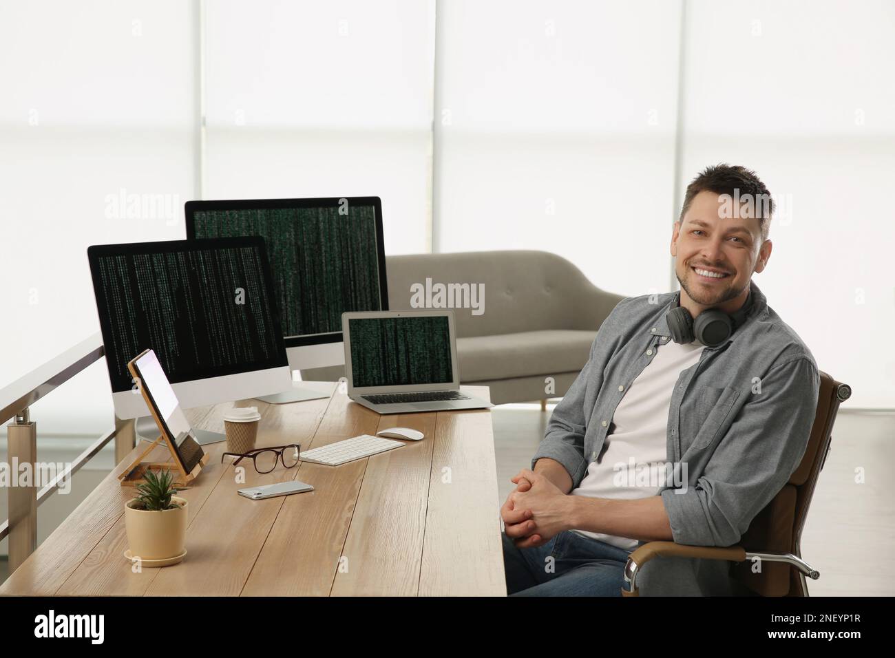Happy programmer with headphones working at desk in office Stock Photo ...