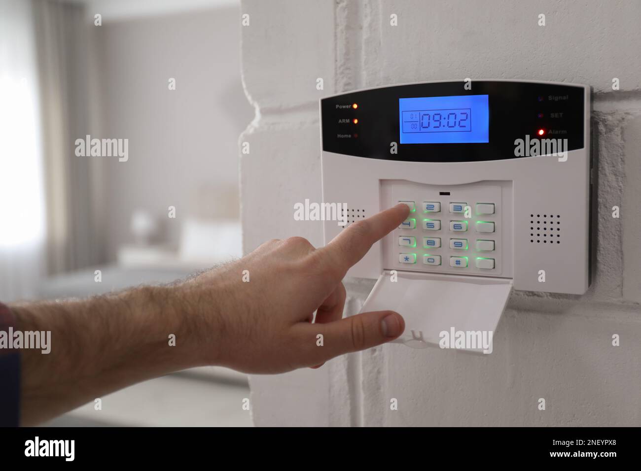 Man entering code on security alarm system at home, closeup Stock Photo ...