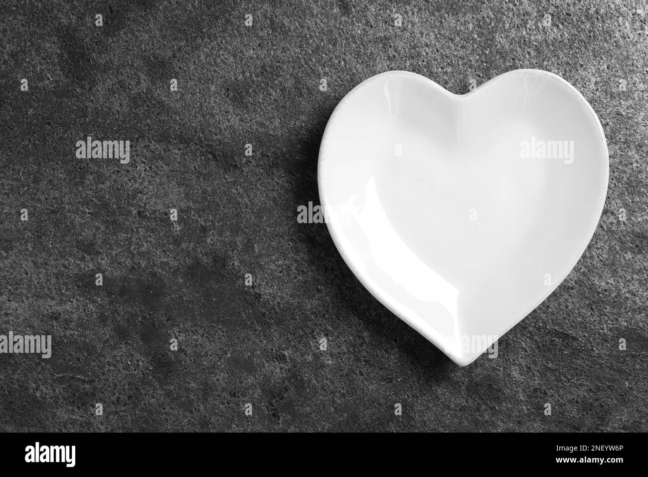 Heart shaped ceramic plate on grey table, top view. Space for text ...