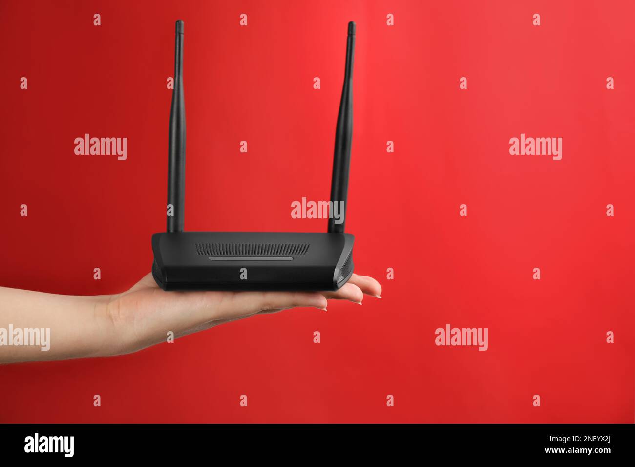 Woman holding modern Wi-Fi router on red background, closeup. Space for ...